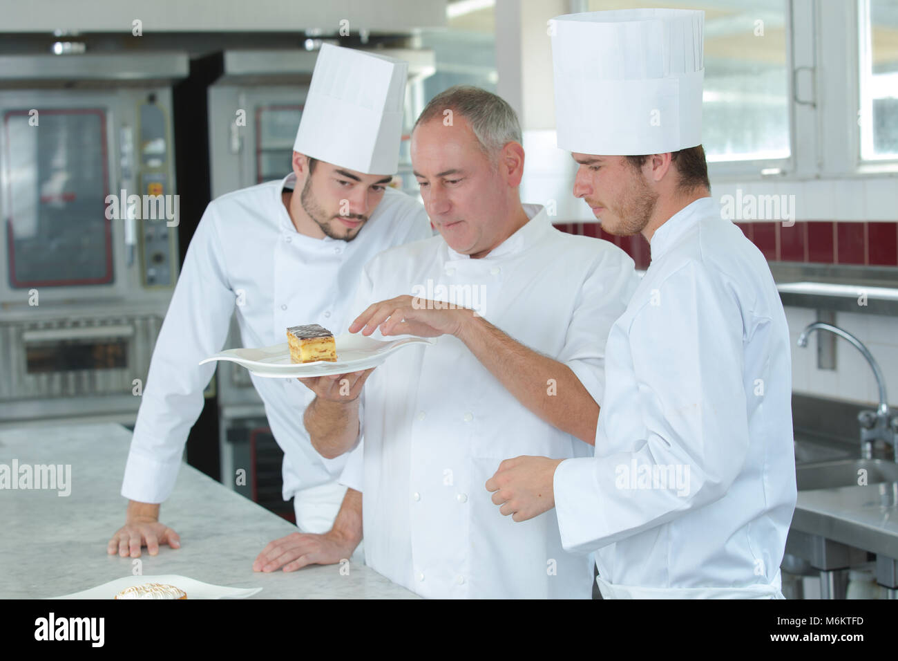 chef and assistants during work in the kitchen Stock Photo - Alamy