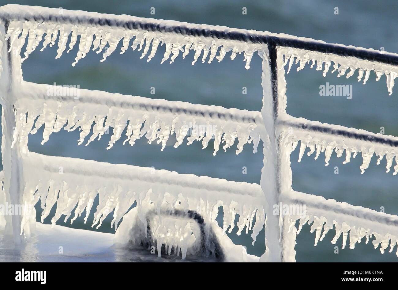 Huge icicles formed by waves hanging on frozen ship's rail, Baltic Sea ...