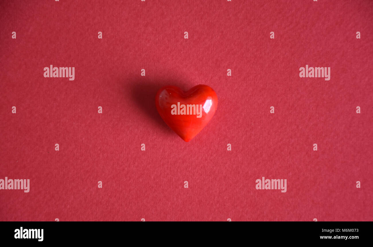 Small red love heart pebble stone against a simple background Stock ...