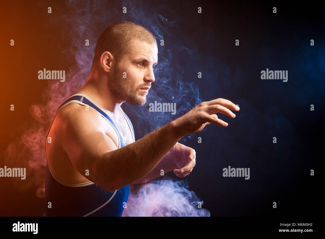 A young sporty man wrestler in a green sports shirt and blue wrestling ...