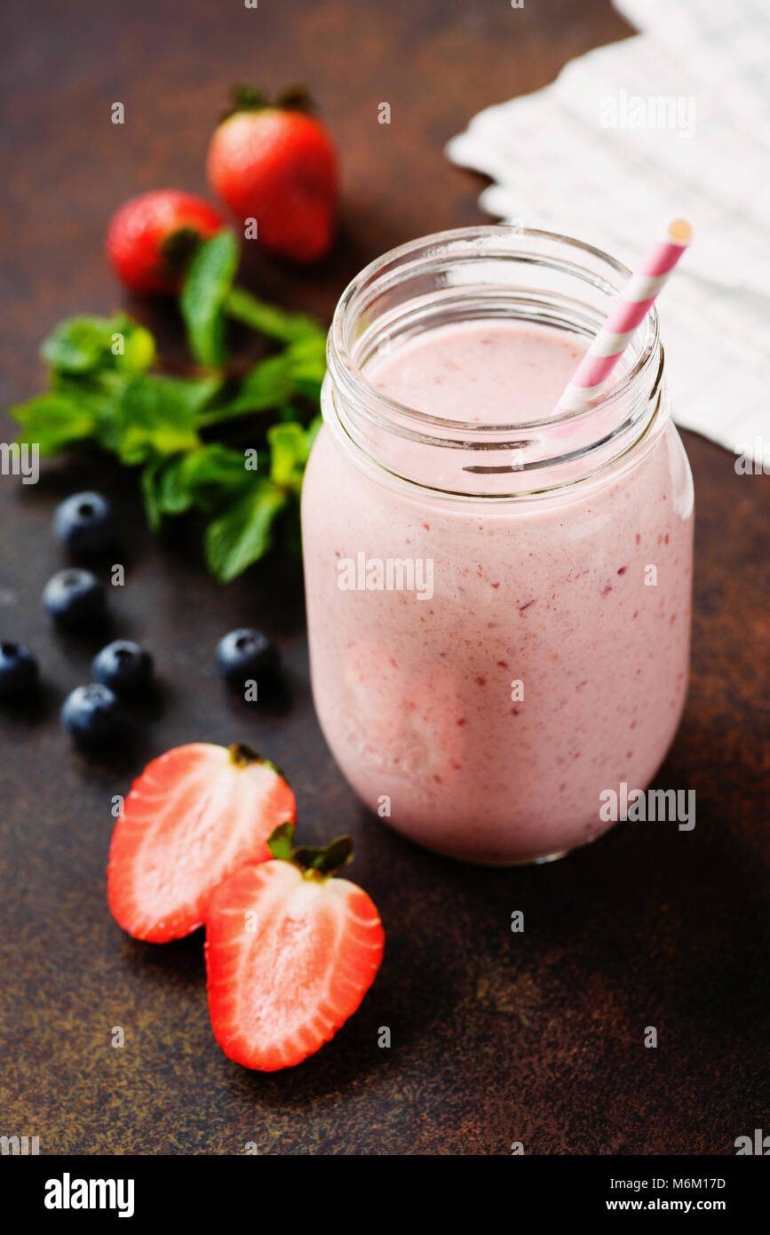 Pink berry smoothie in jar on dark background, closeup view, selective ...