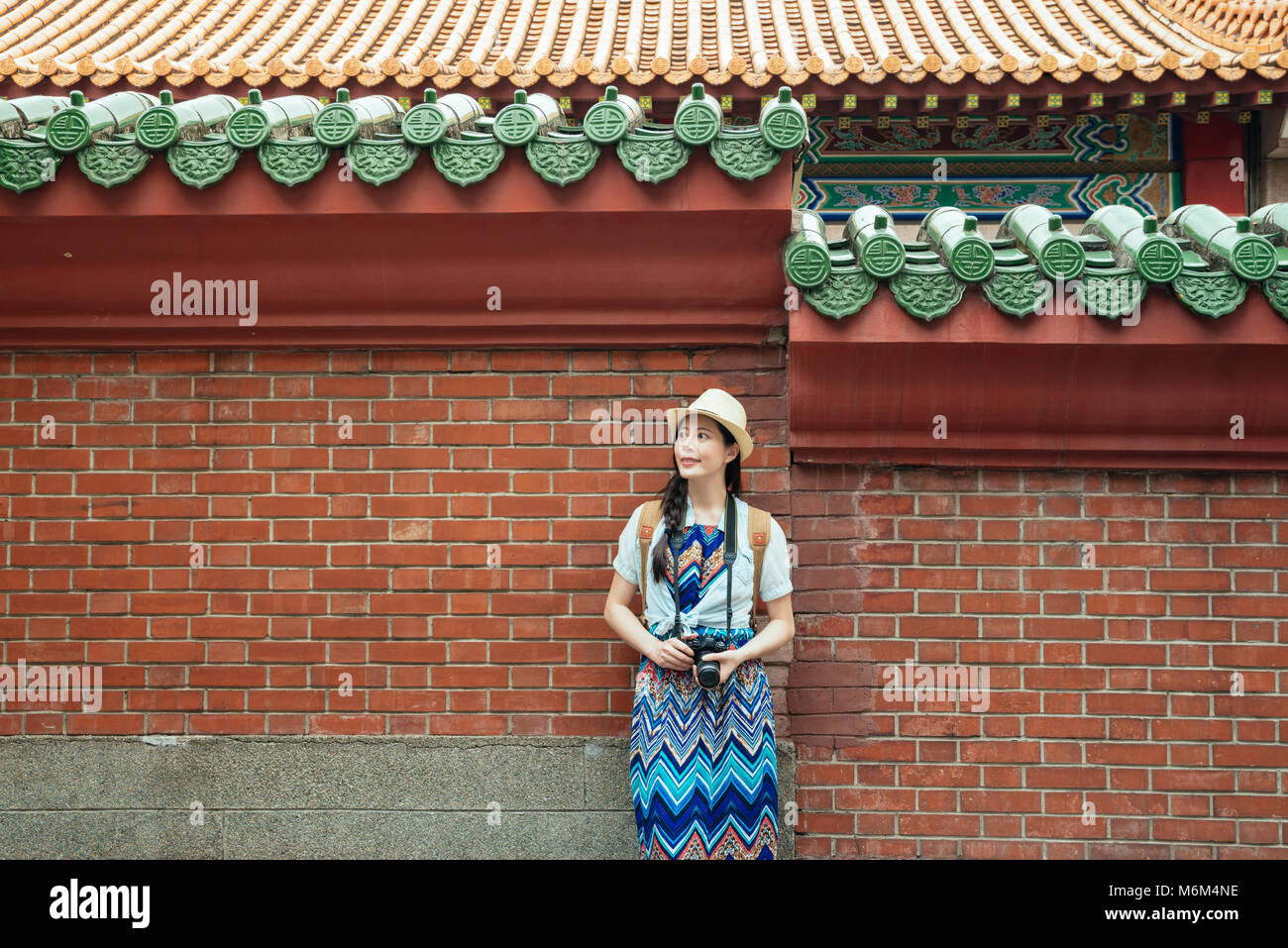 Beautiful woman rest beside old traditional chinese red brick wall at ...