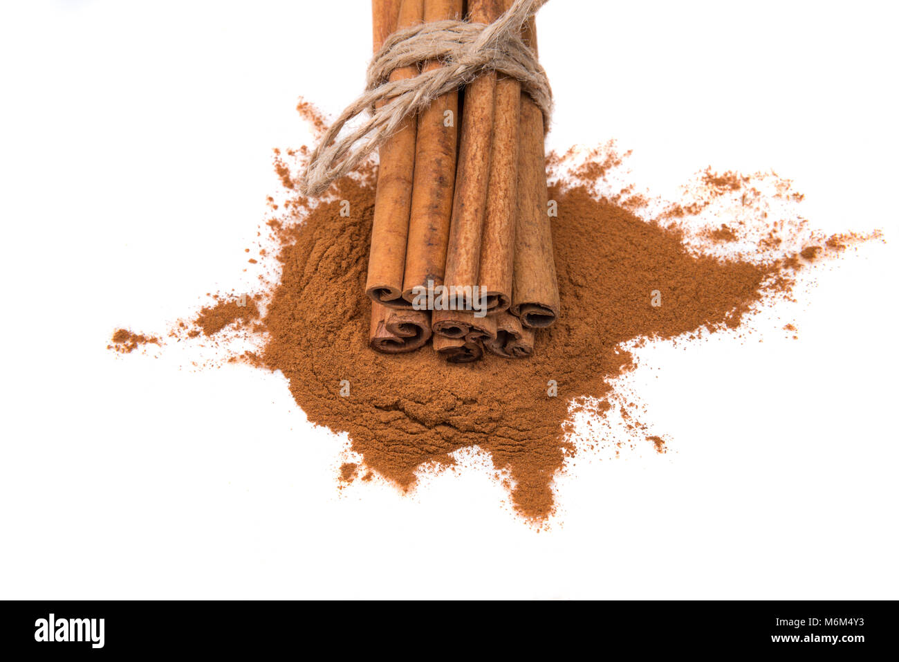 Cinnamon sticks tied with a rope on cinnamon powder, isolated on white ...