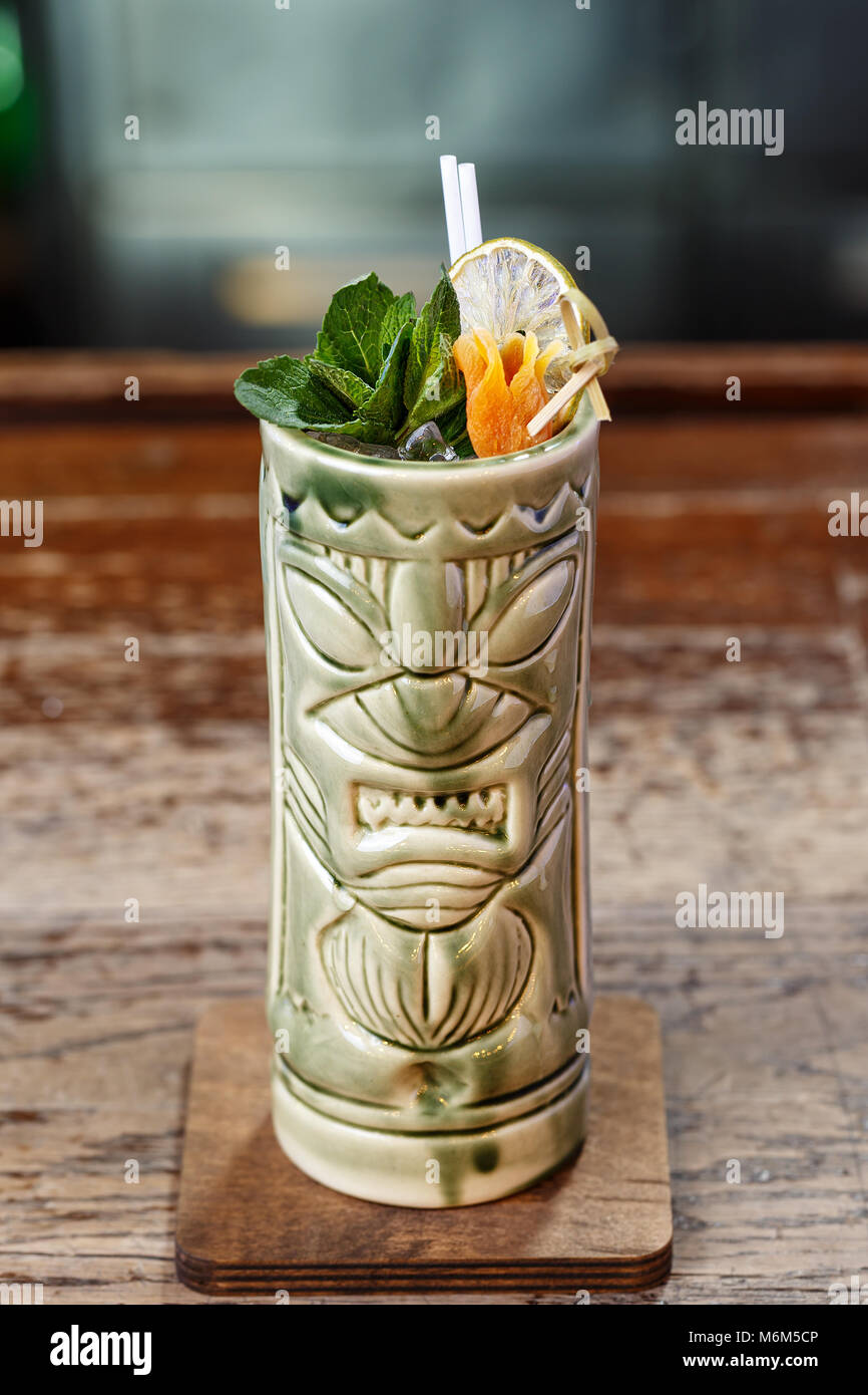 Cocktail in a glass of tiki on a bar counter on a blurred background of ...