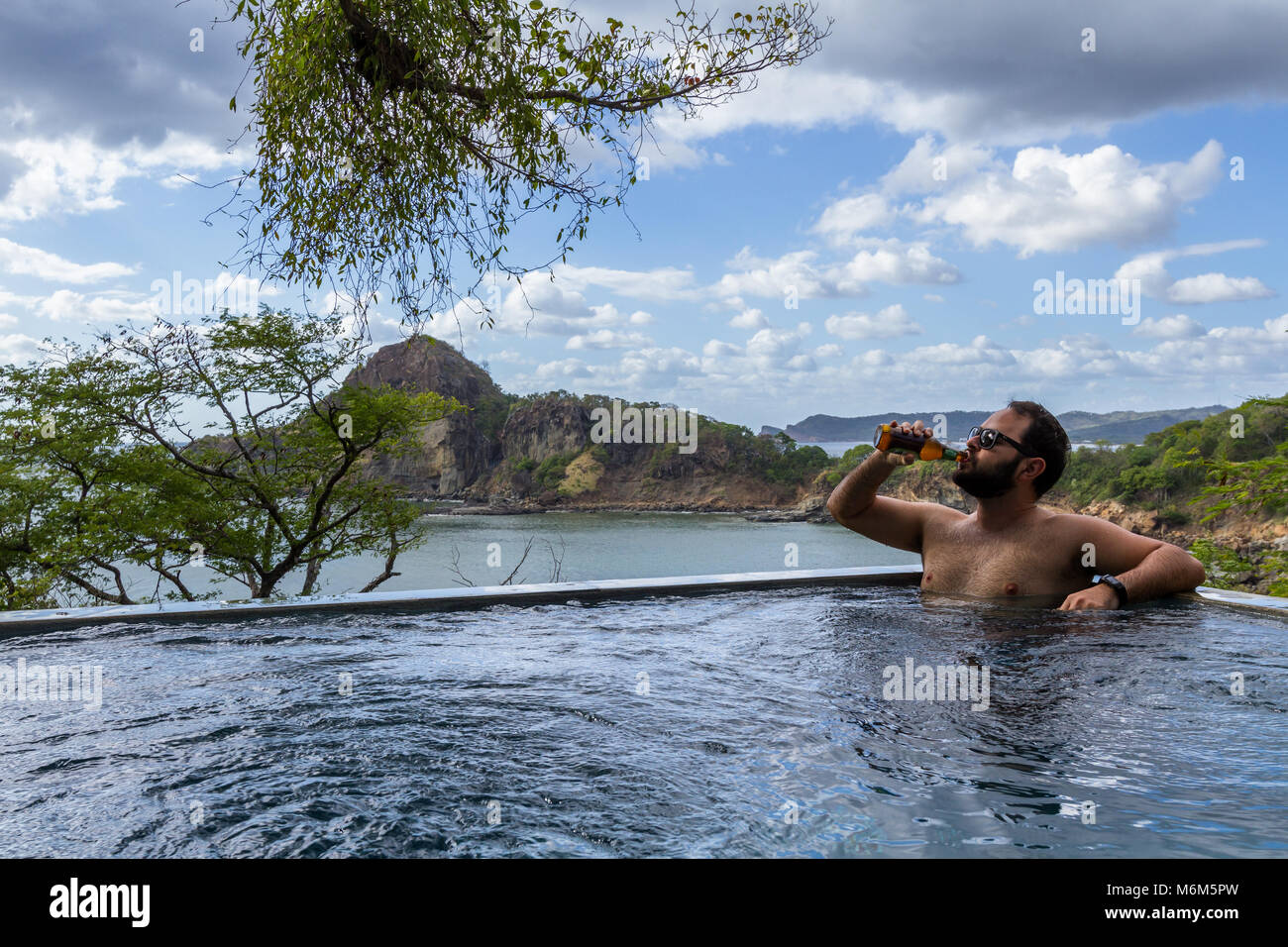 man relaxing in a calm pool with an amazing view of the pacific ocean ...