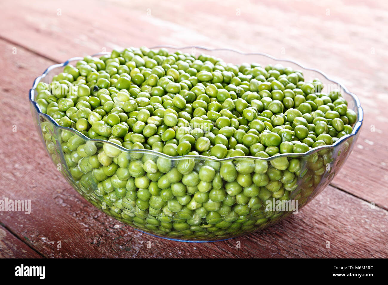 Young green peas peeled in a plate on a wooden background Stock Photo ...
