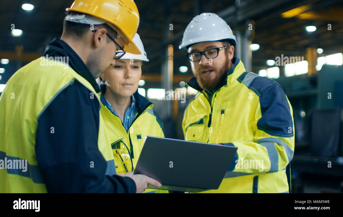 Three Industrial Engineers Talk with Factory Worker while Using Laptop ...