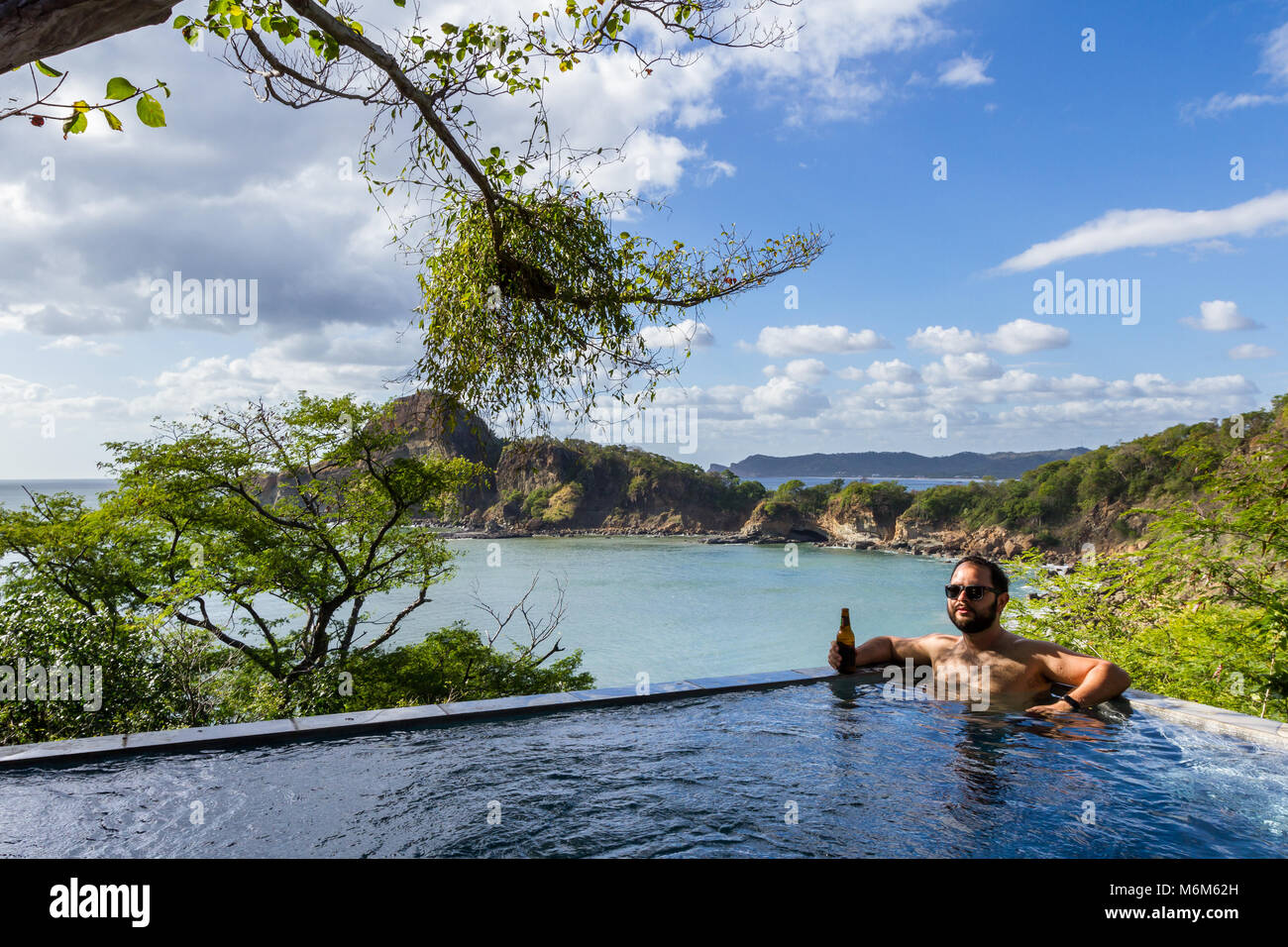 man relaxing in a calm pool with an amazing view of the pacific ocean ...