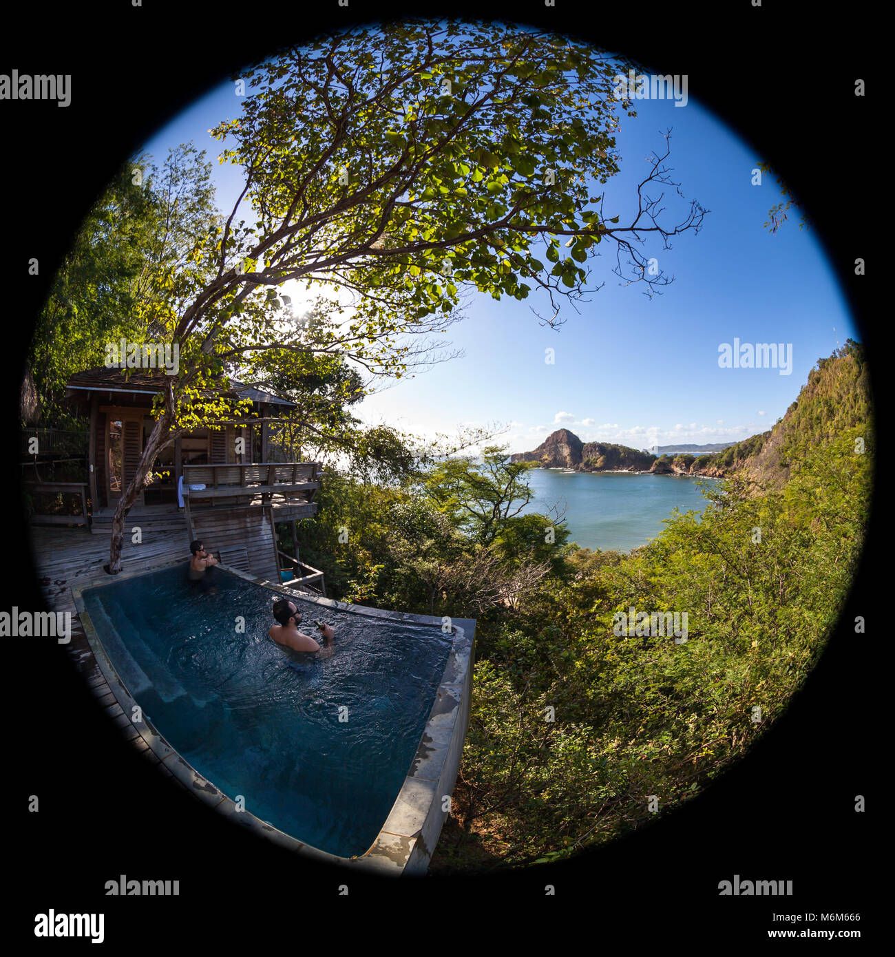 two men relaxing in a peaceful pool overlooking the pacific ocean in ...