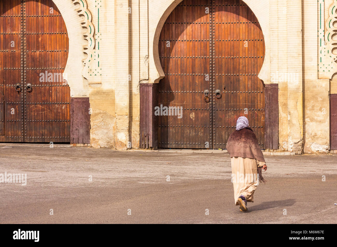 Local woman in traditional clothing walks in front of Bab Dkaken, Fes ...