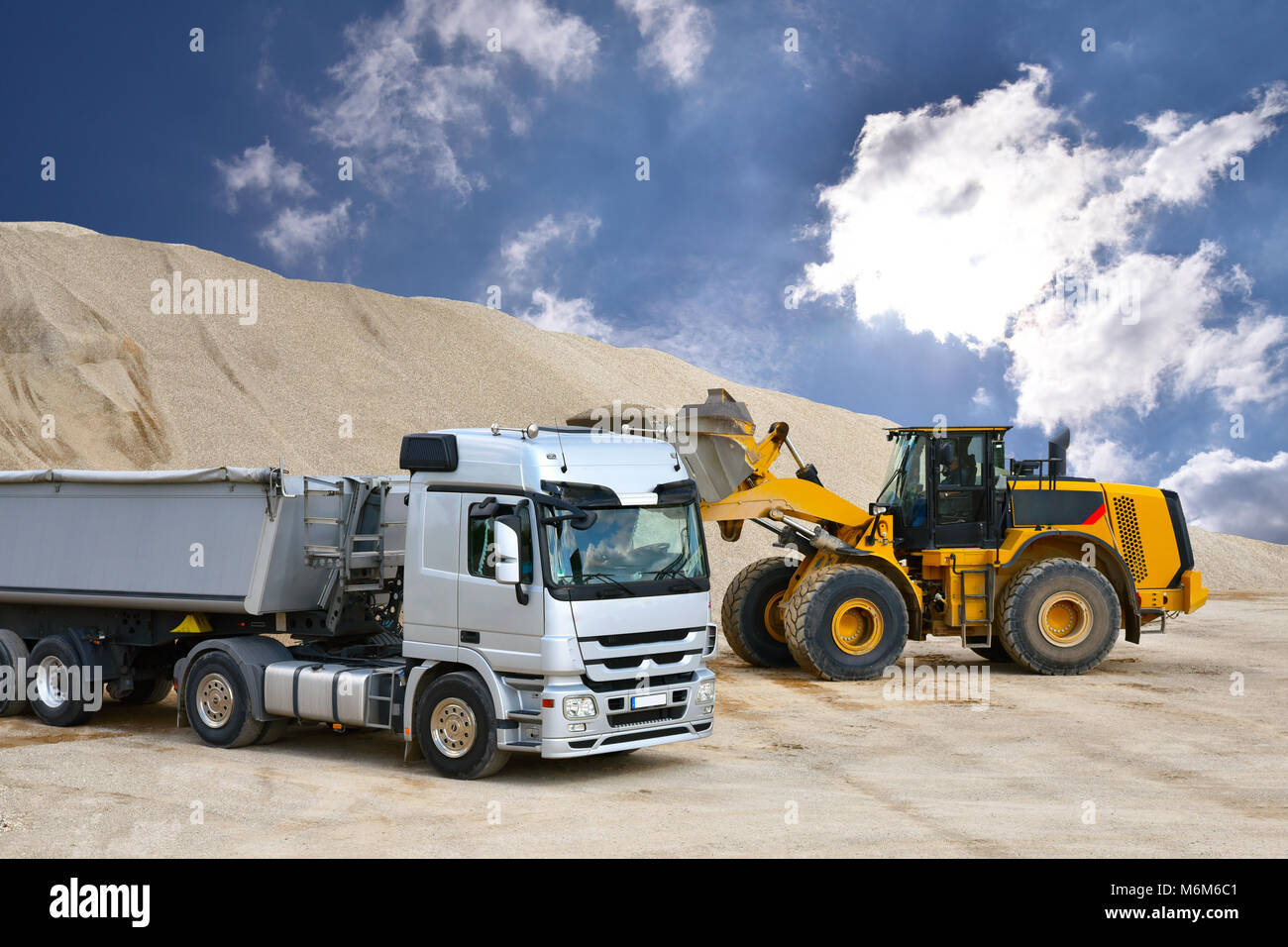 Wheel loader loads a truck with sand in a gravel pit Stock Photo - Alamy