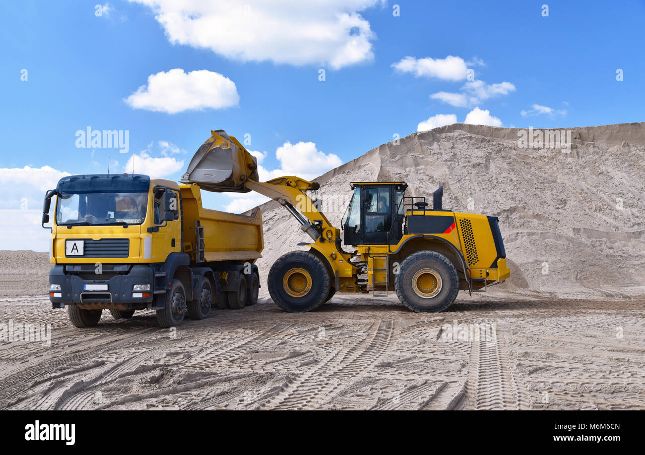 Wheel loader loads a truck with sand in a gravel pit Stock Photo - Alamy