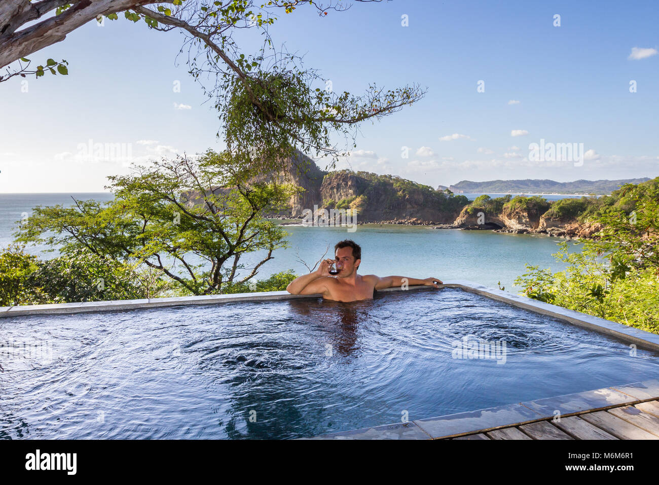 man relaxing in a calm pool with an amazing view of the pacific ocean ...