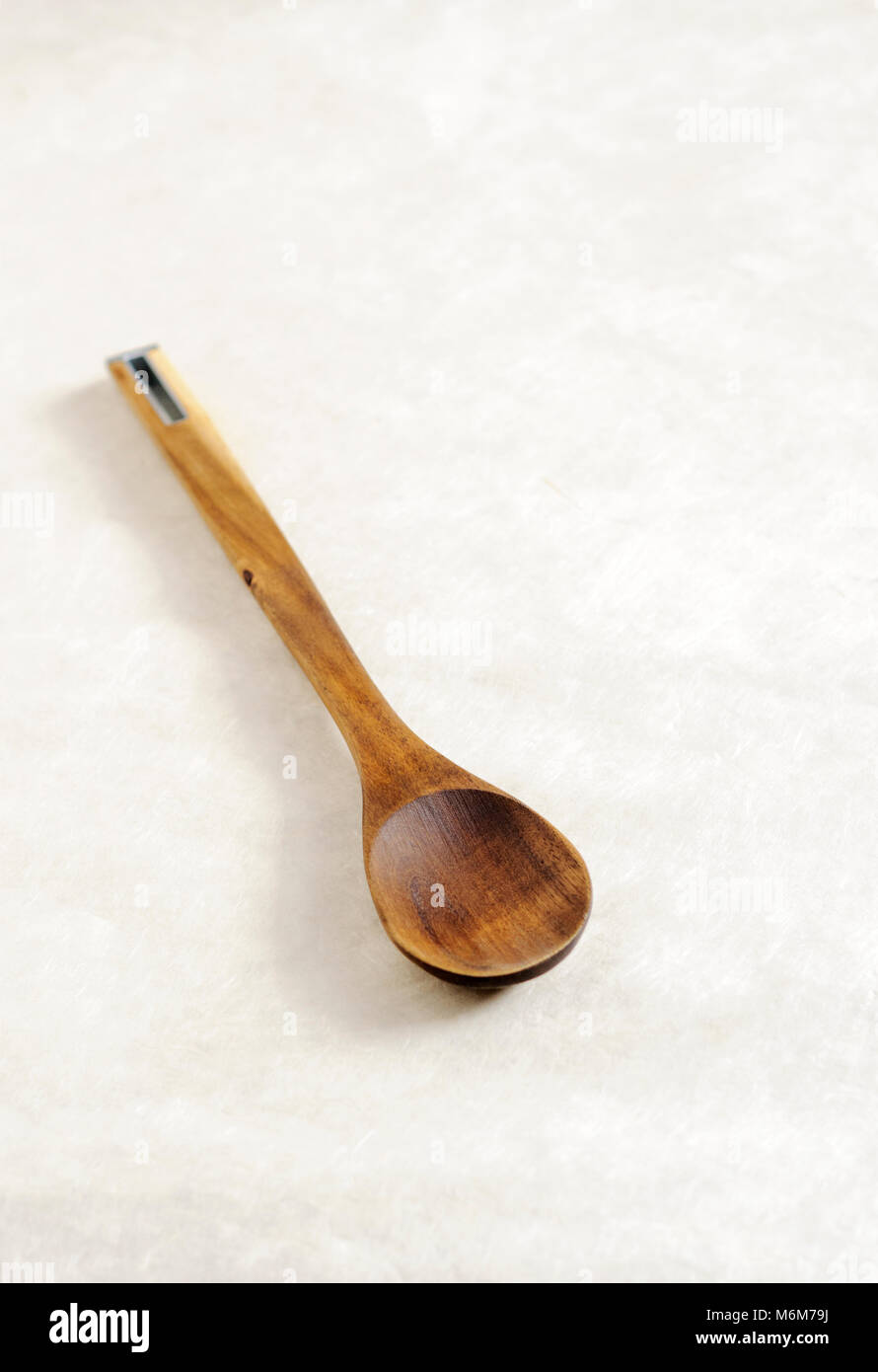 Large, rustic serving spoon made of wood on a neutral parchment paper ...