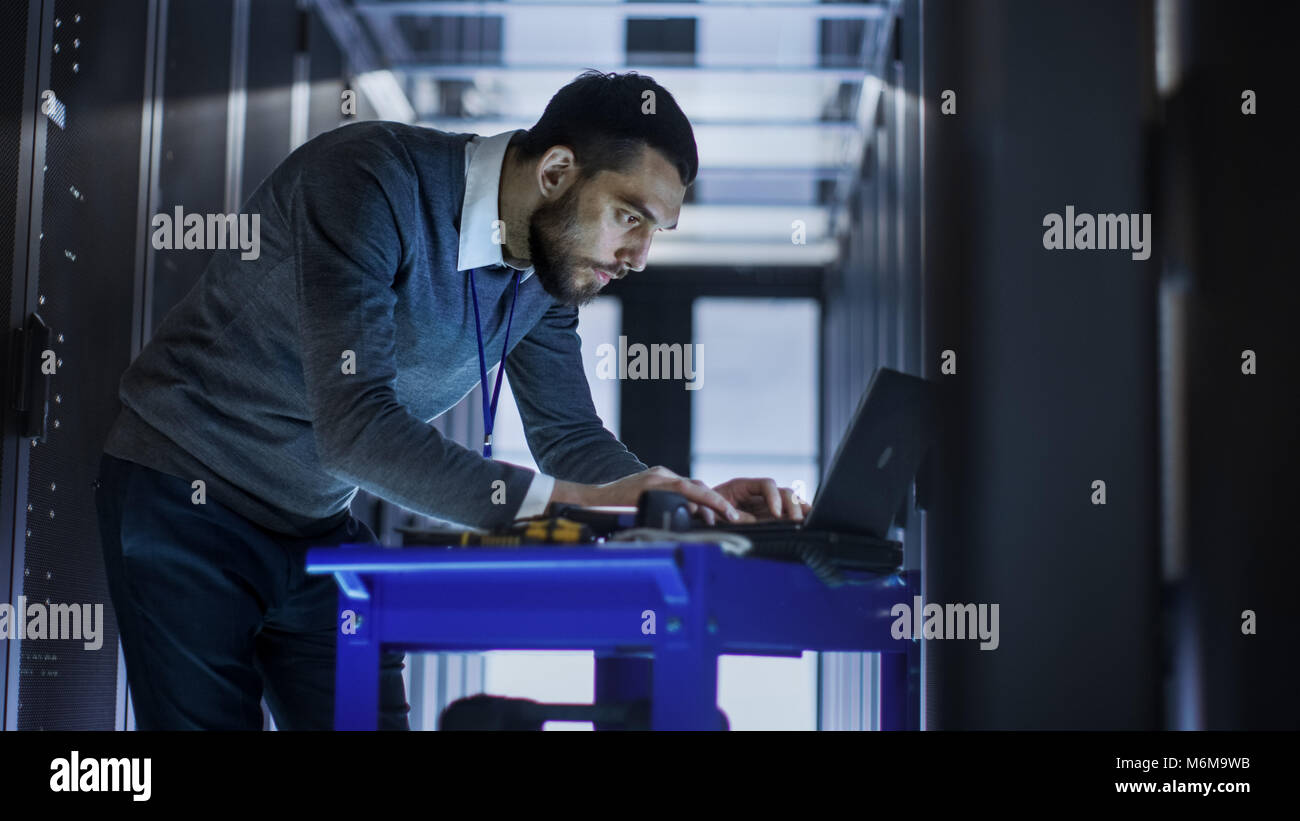 IT Engineer with Tool Cart Working on a Laptop Computer, he Deploys new ...