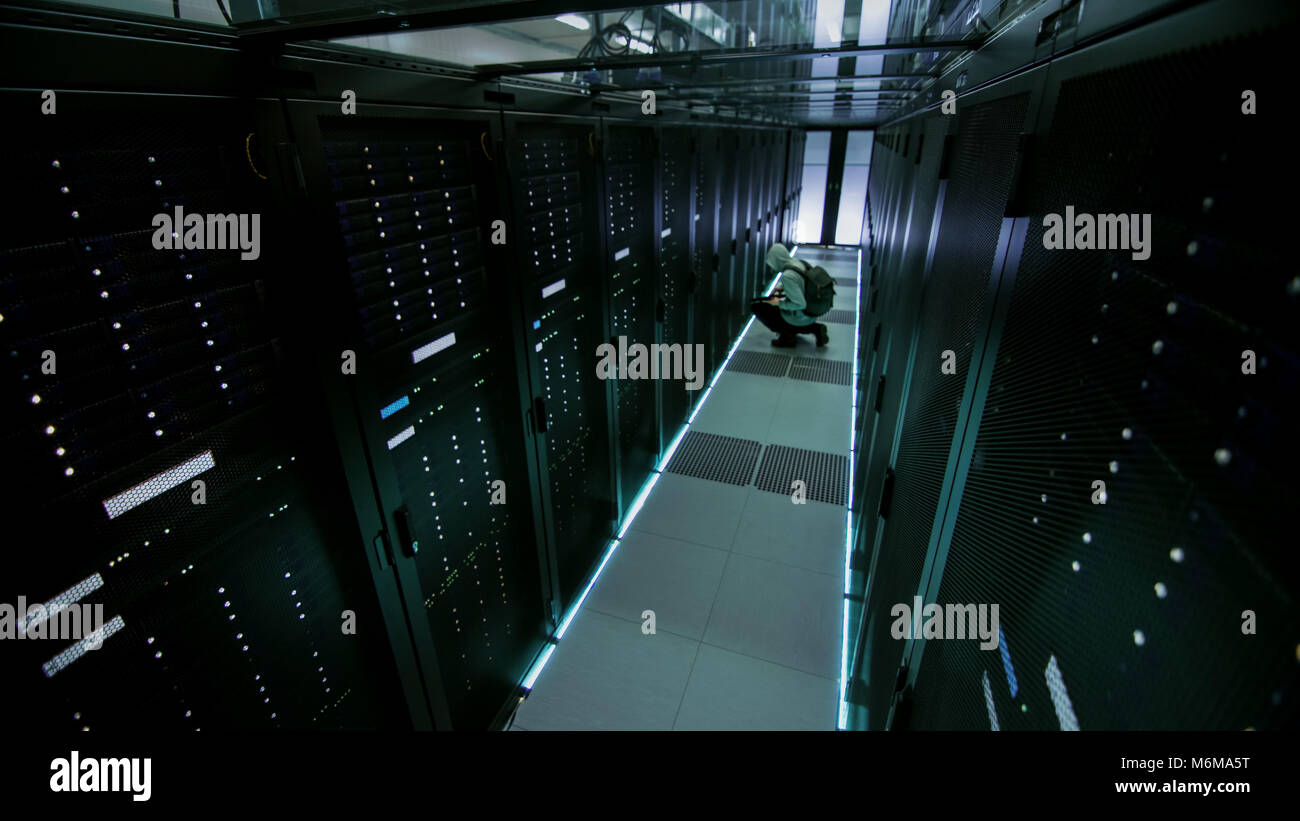 Security Camera view of a Hooded Hacker in Data Center, With His Laptop ...