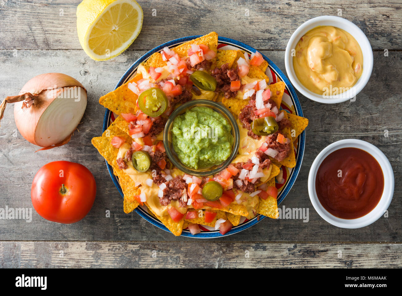 Mexican nachos with beef, guacamole, cheese sauce, peppers, tomato and ...