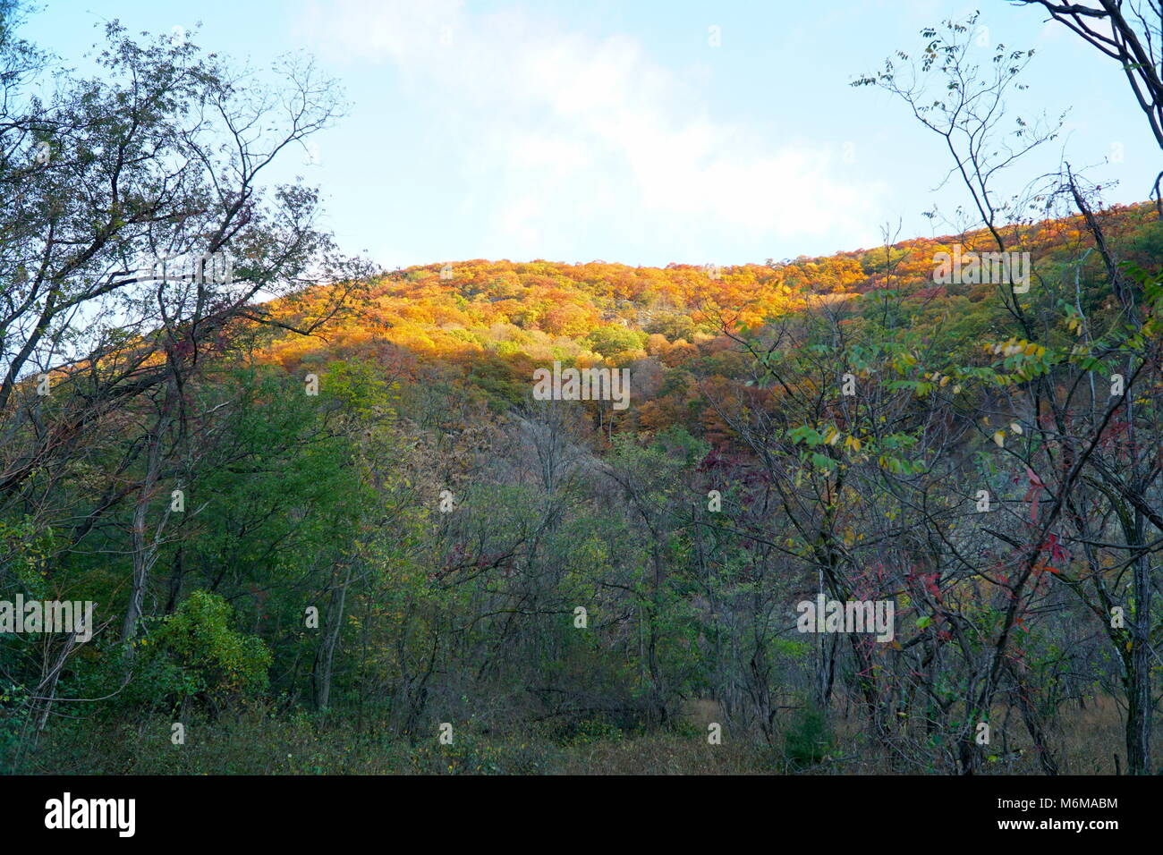 Mountainside sunrise with morning light cast shadow across fall autumn ...