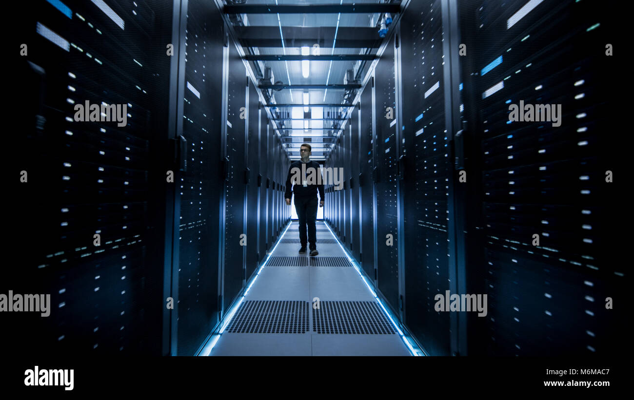 Shot of IT Engineer Walking Through Data Center Corridor with Rows of ...