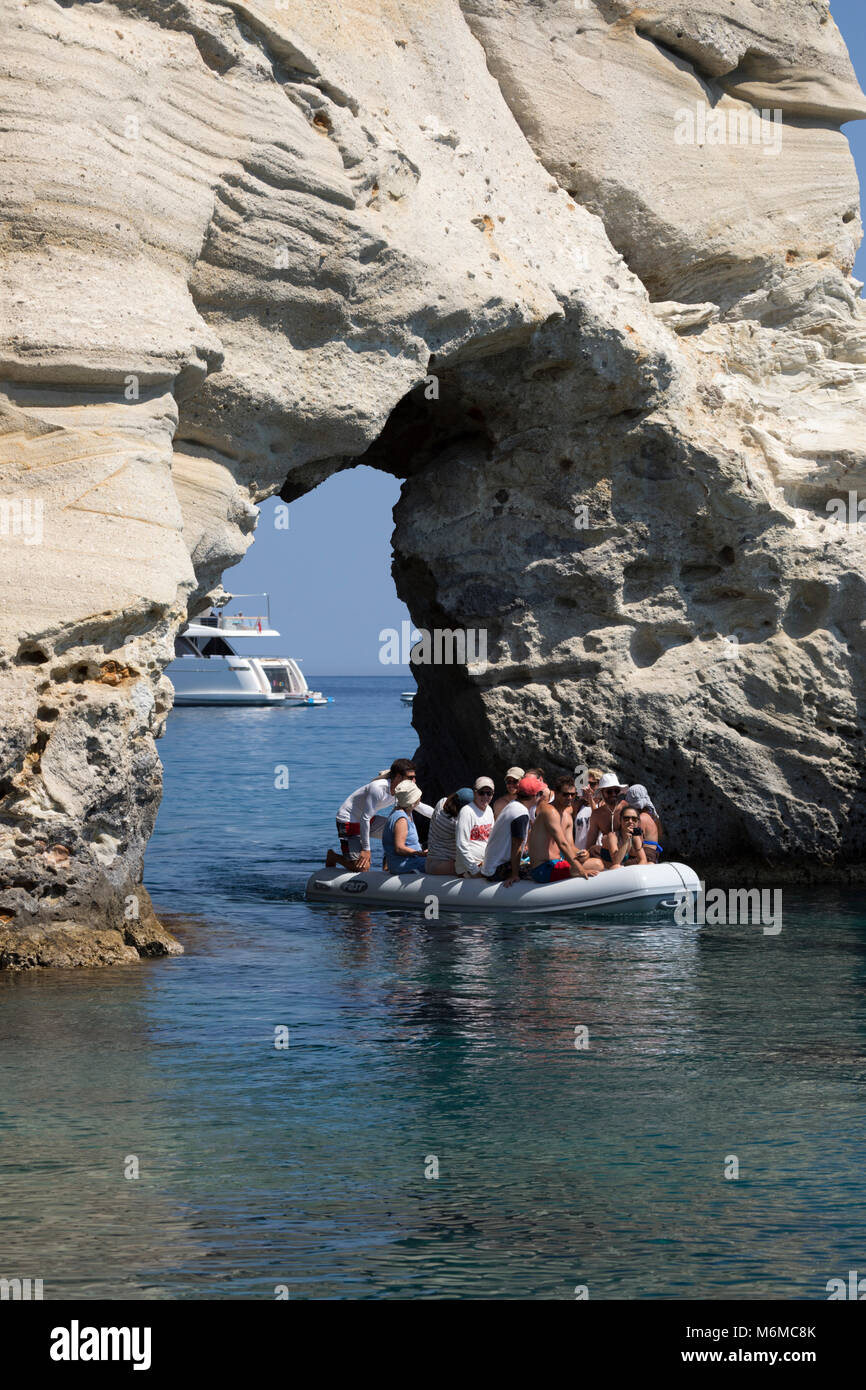 Inflatable boat going through arch rock formation with crystal clear ...