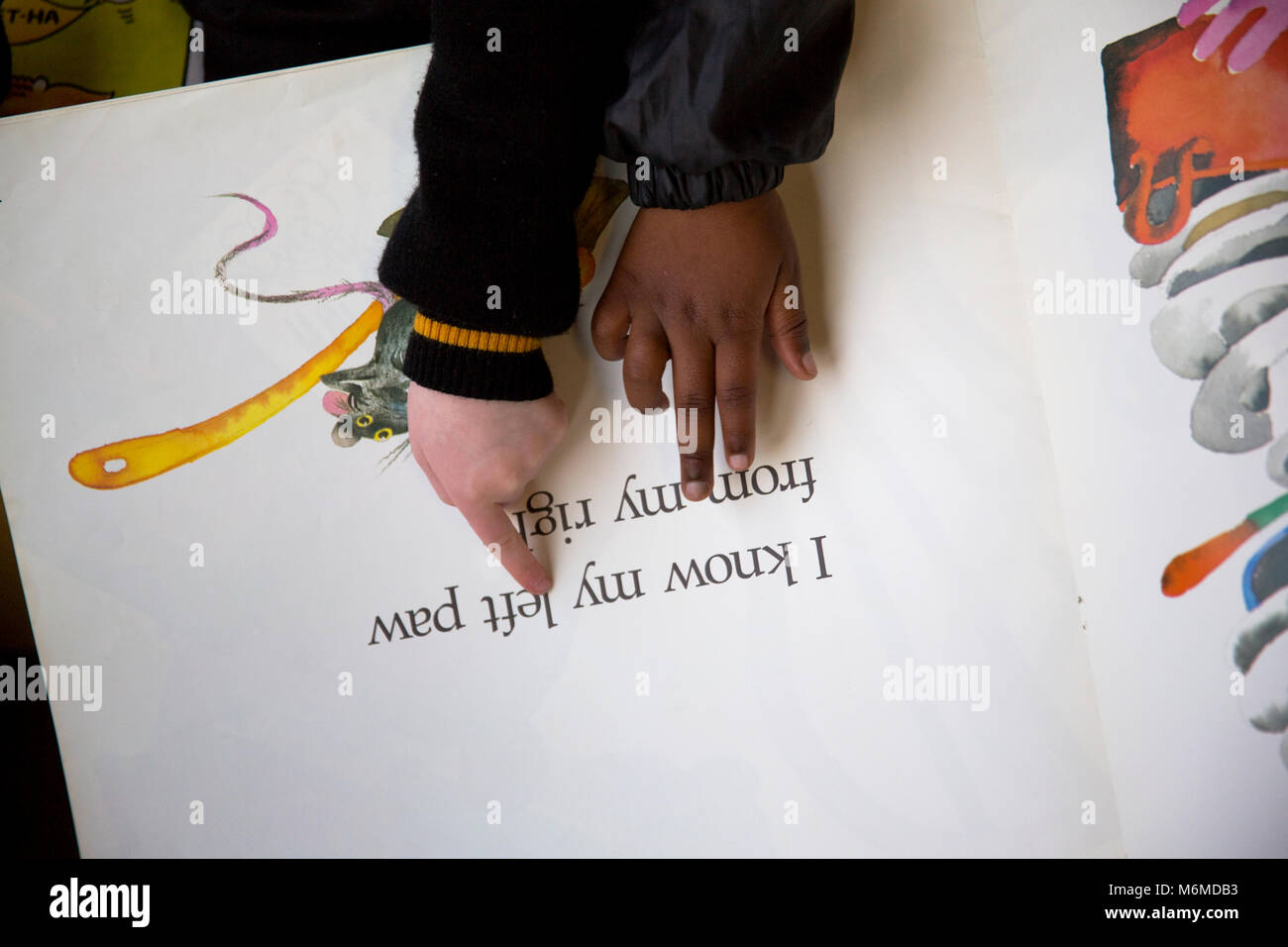 Close up of school kids pointing words in a book Stock Photo - Alamy