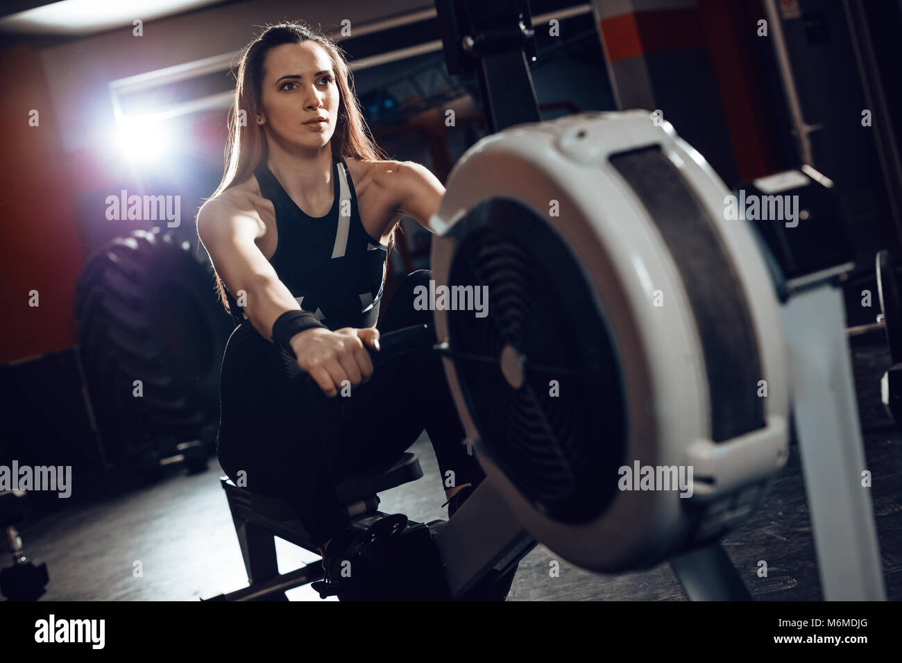 Young muscular cute woman pulling the rowing machine at the gym Stock ...