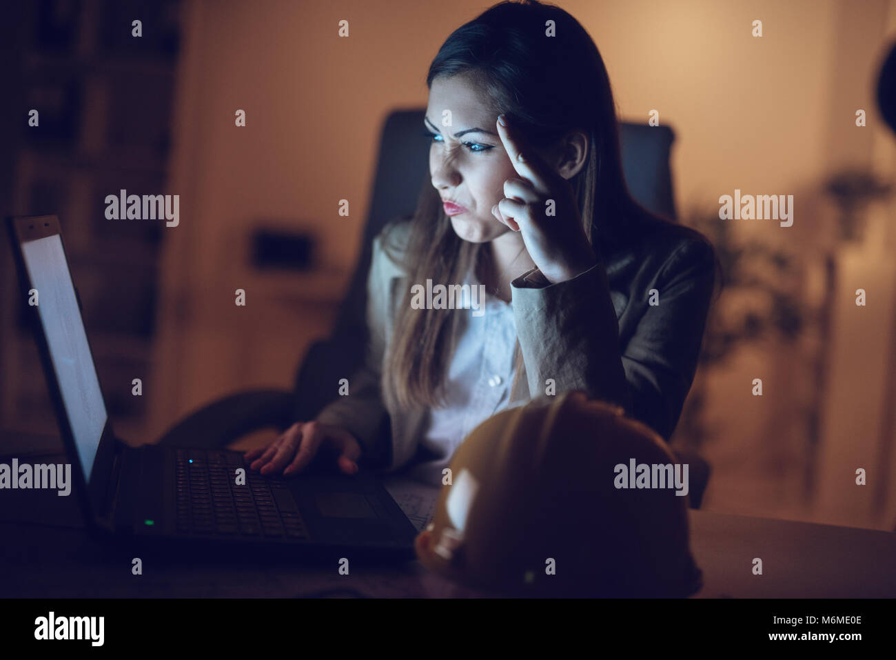 Worried lonely young woman looking at lighted screen of a laptop in ...