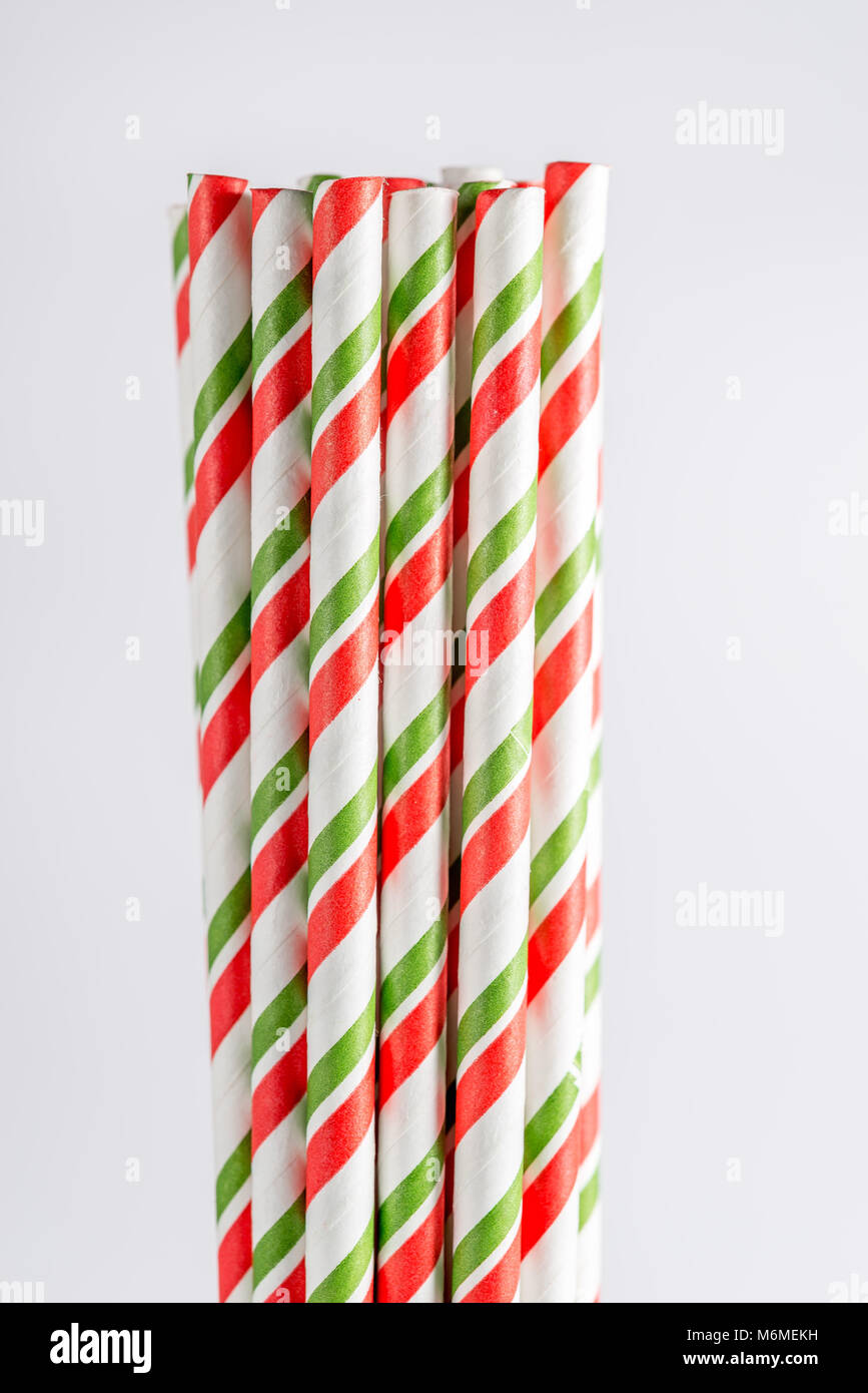 Red, green and white plastic striped straws on a white background ...