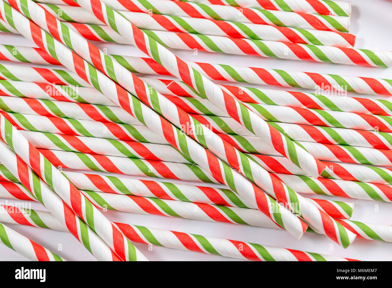 Red, green and white plastic striped straws on a white background ...