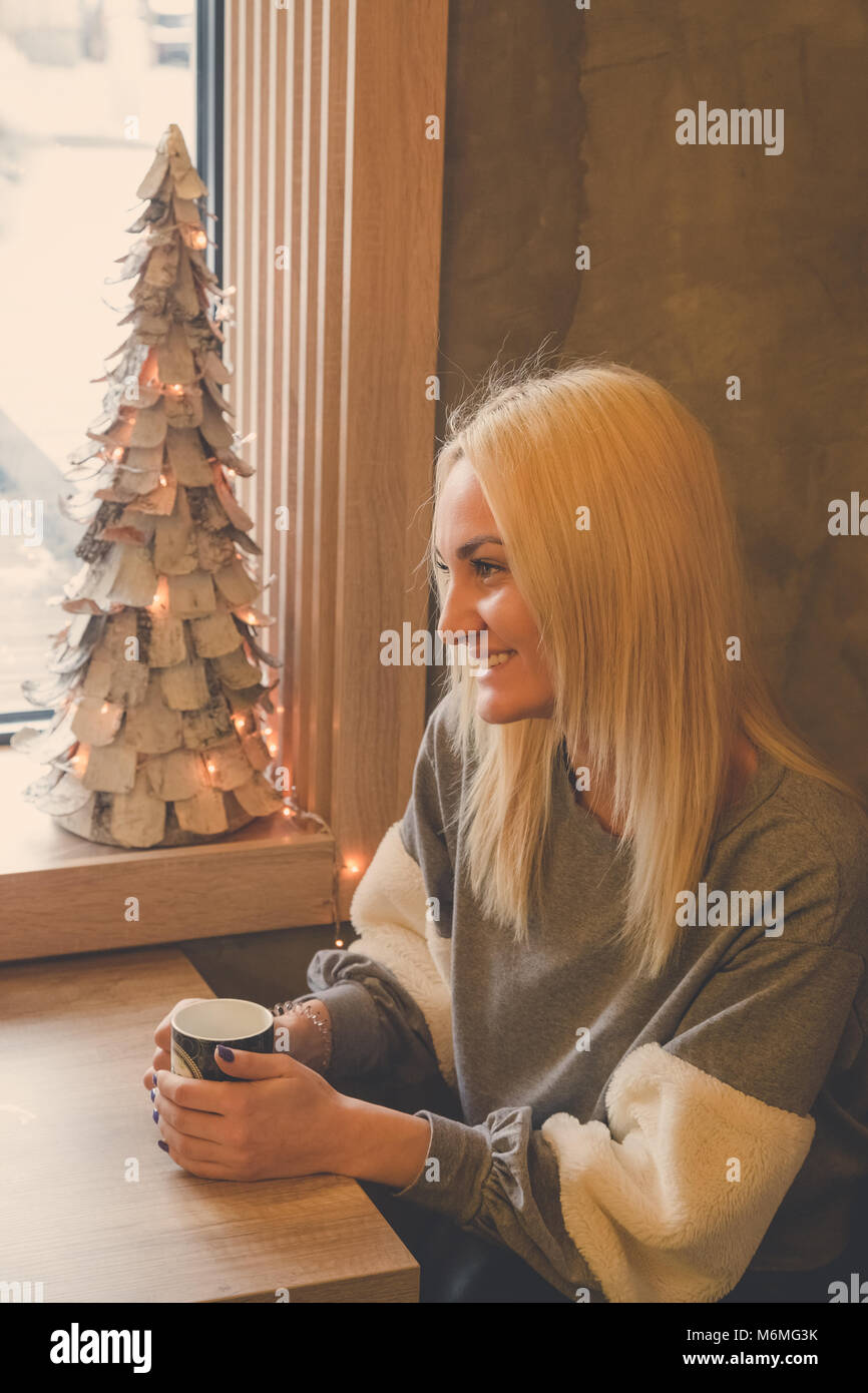 Portrait of young woman enjoying her morning tea at the desk next to ...