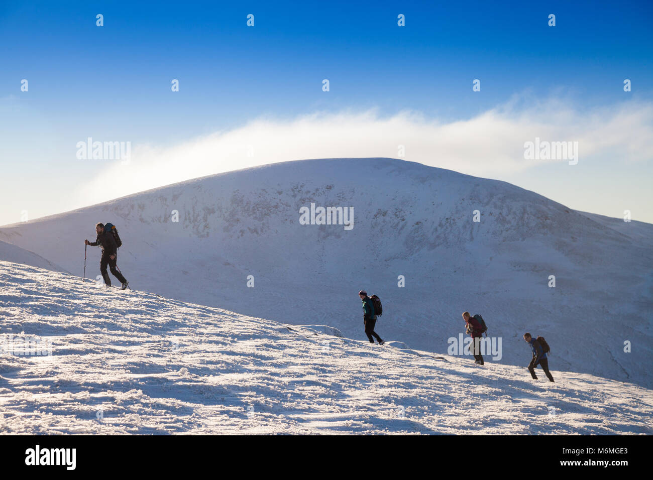 Four people walking up the ridge to the Scottish Munro A’Mharconaich ...