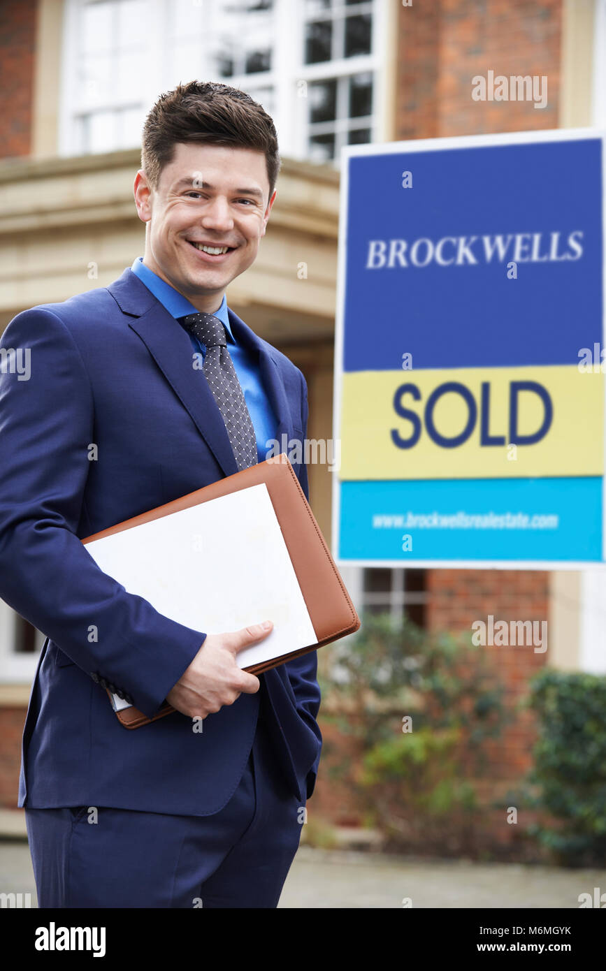 Male Realtor Standing Outside Residential Property With Sold Sign Stock ...