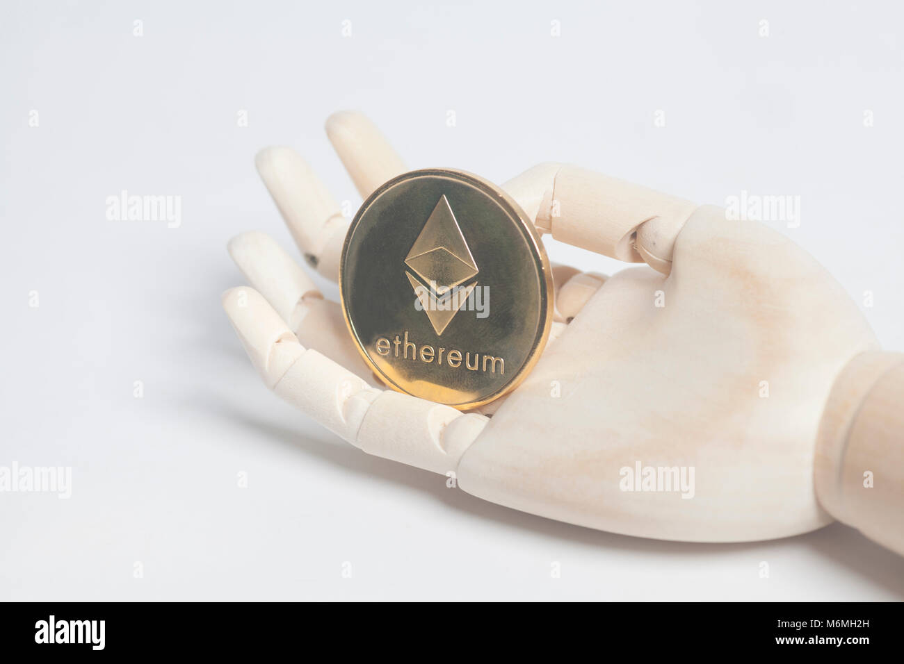 Wooden robot cyborg hand holding golden Ethereum on white Stock Photo ...