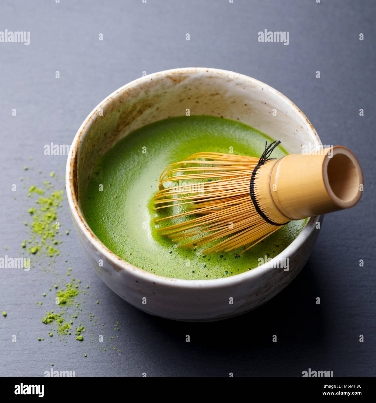 Matcha green tea cooking process in a bowl with bamboo whisk. Black ...