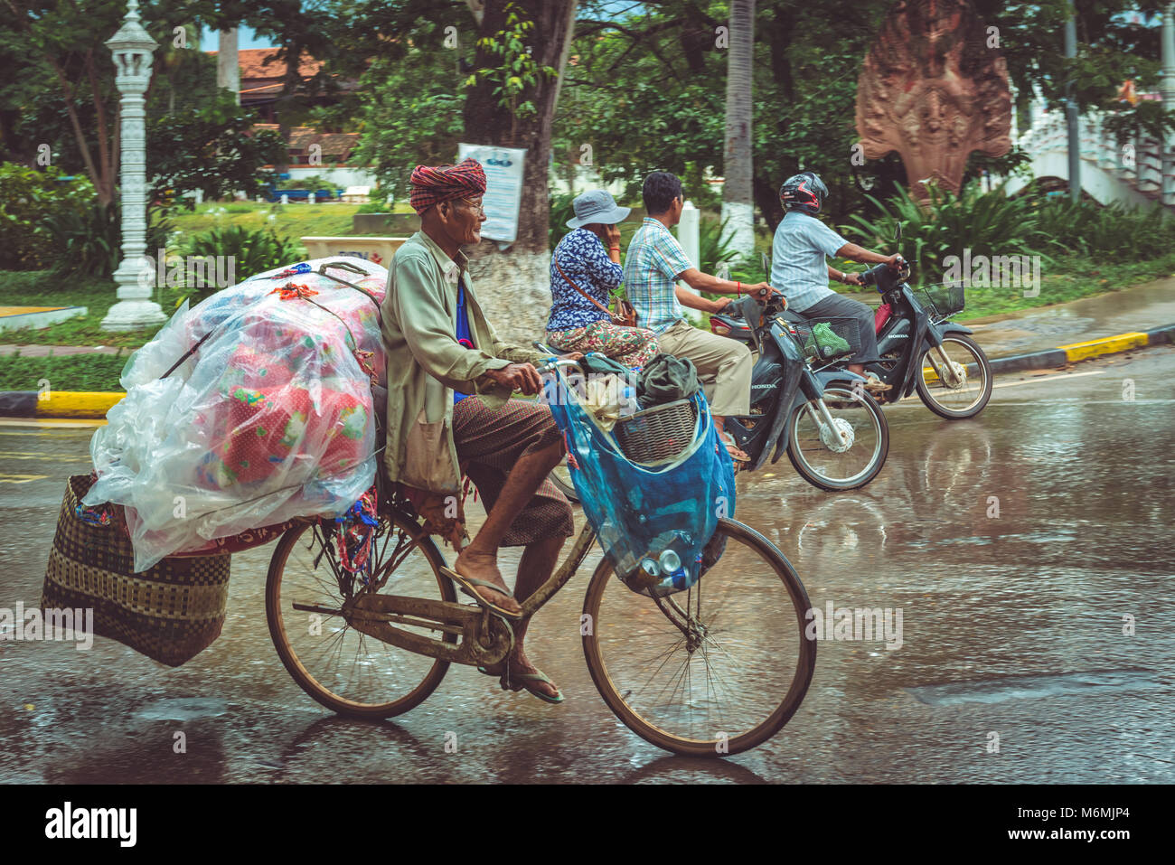 People on mopeds and bicycles transporting passengers and goods through ...
