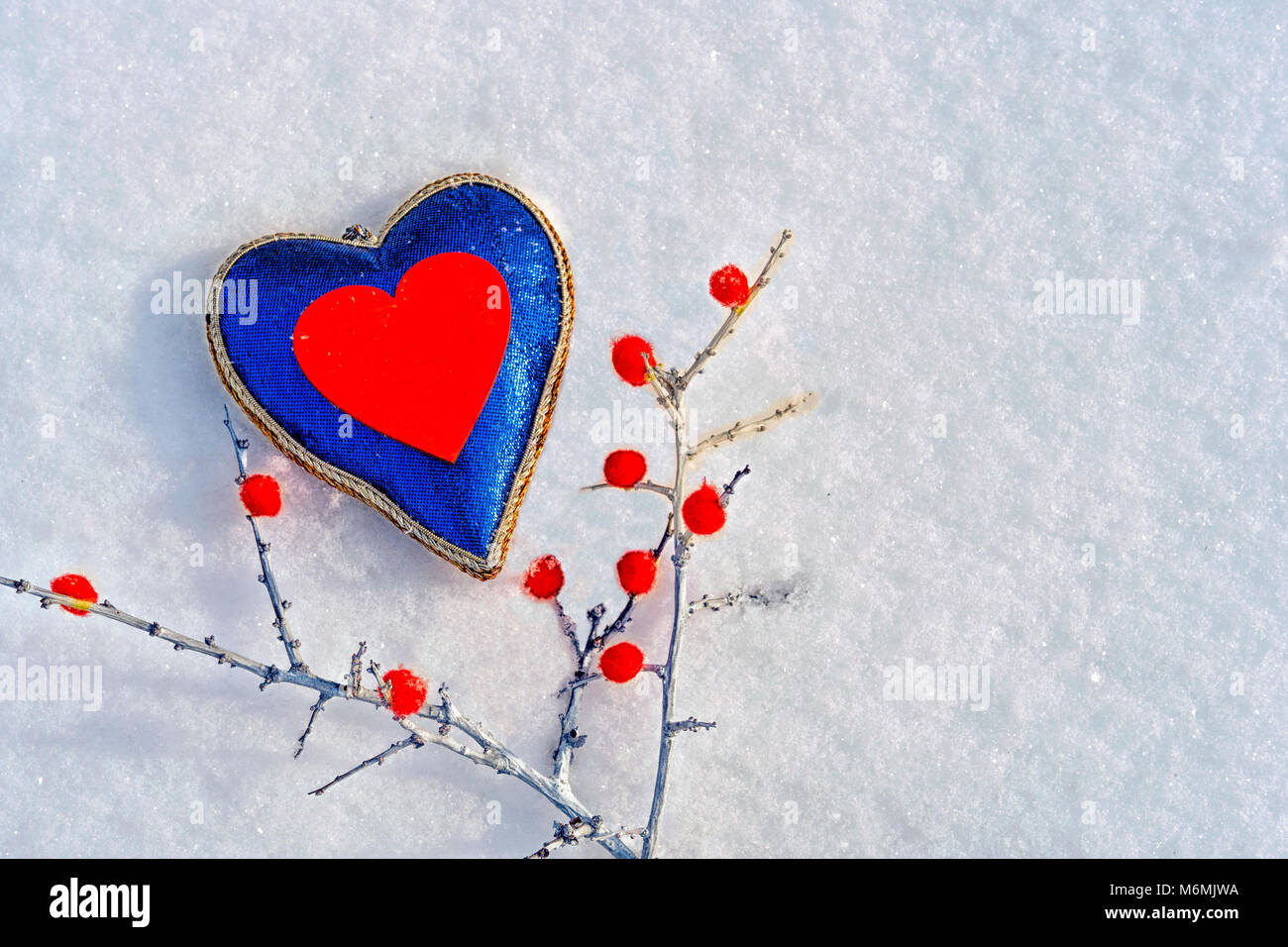 The shape of a blue and red heart in the snow in winter, a branch with ...