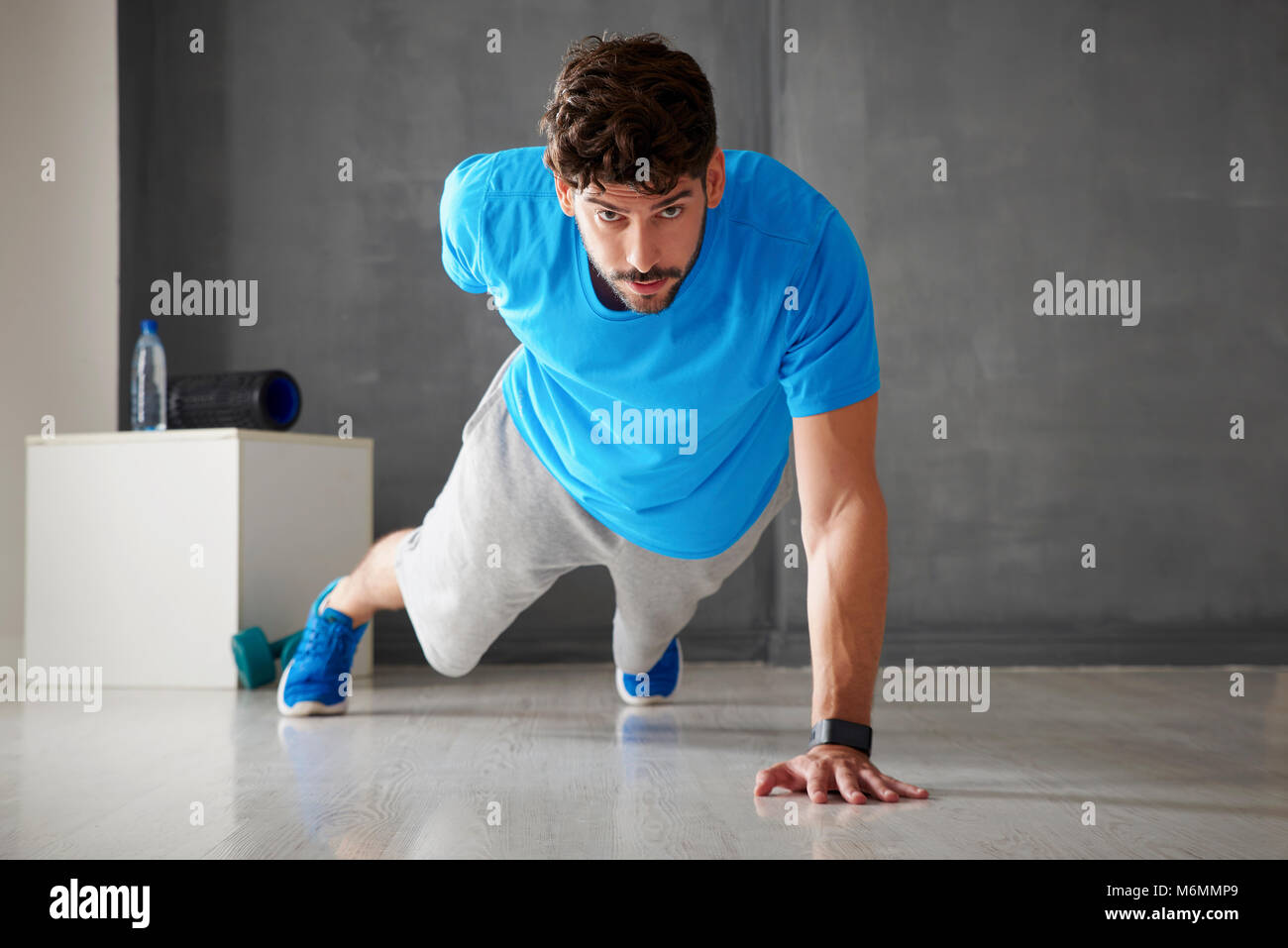 Full length shot of a young man doing a one handed push up in the gym ...