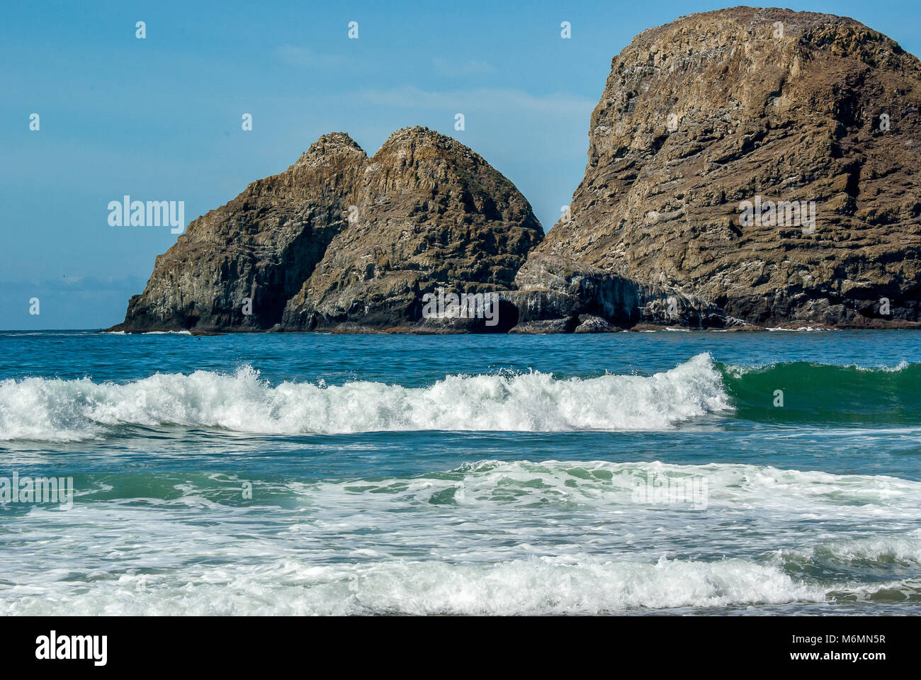 shoreline with incoming waves and large rocks in background Stock Photo ...