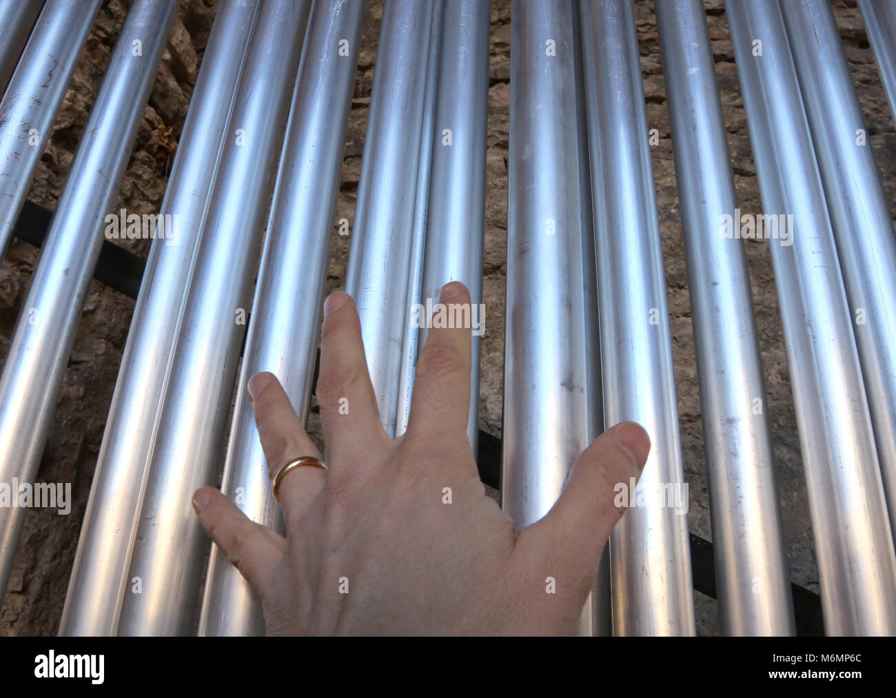 man's hand with wedding ring while playing the empty metal rods of a ...
