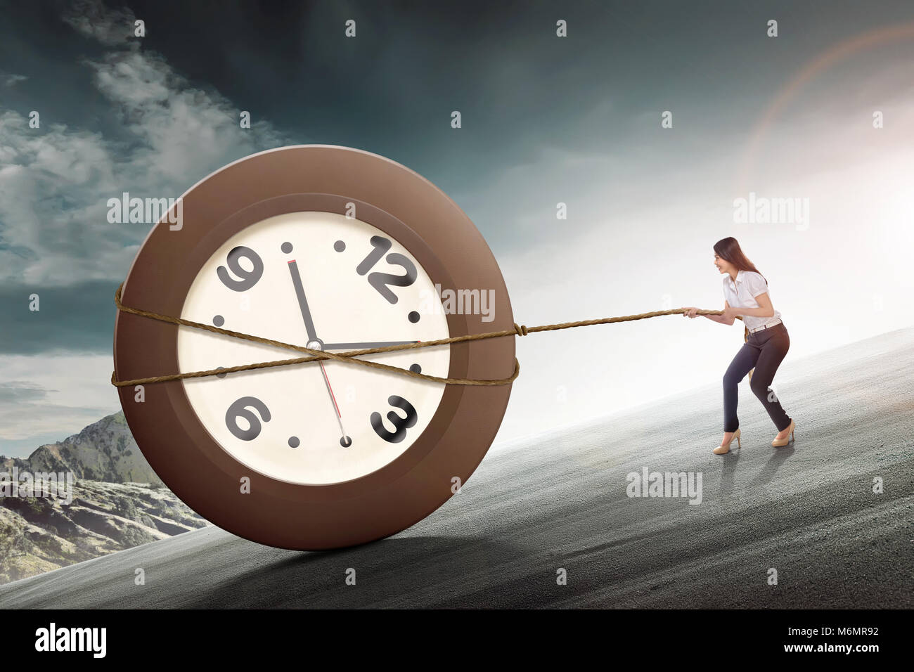Young asian business woman pulling clock with rope to uphill mount ...