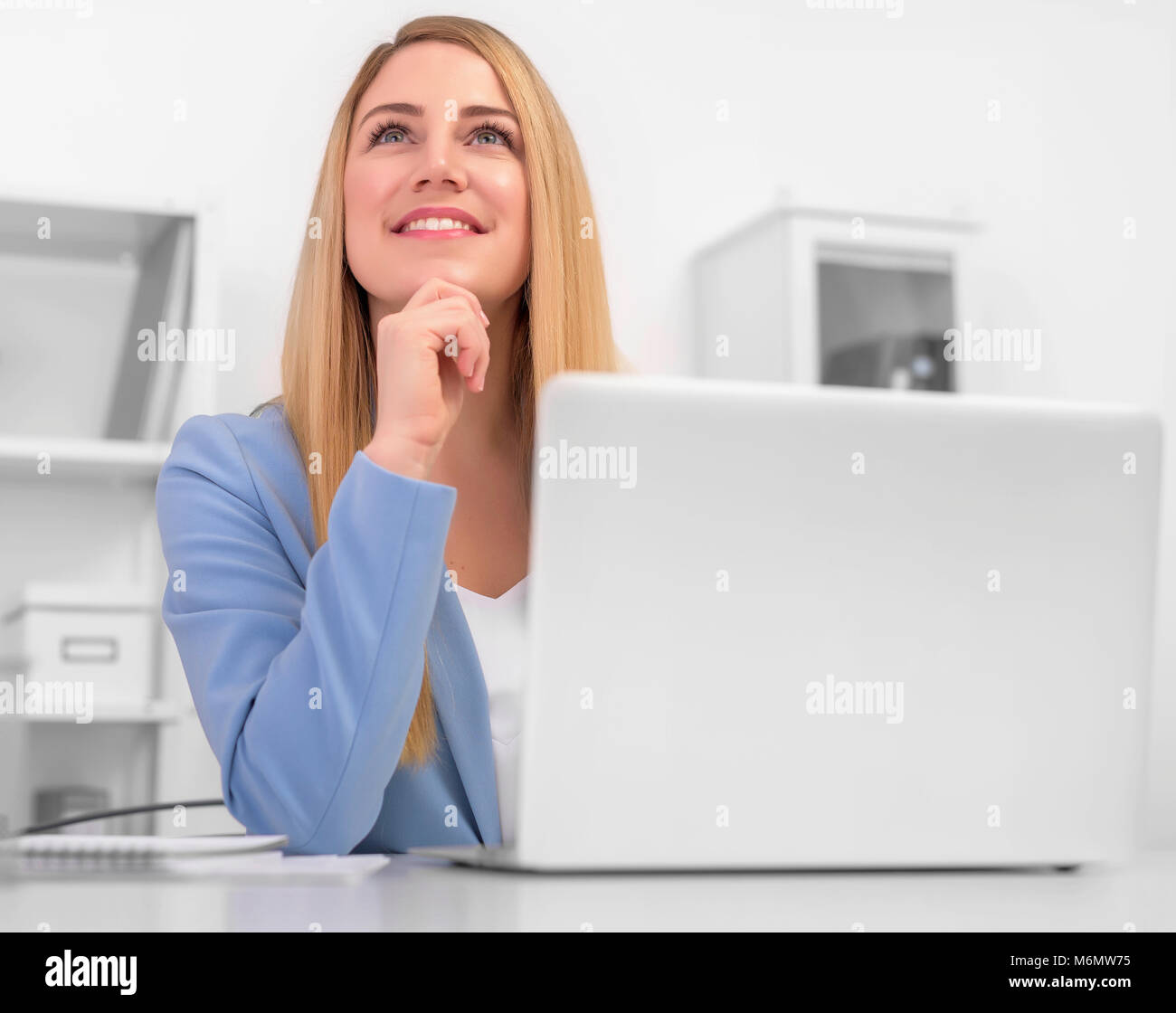 Attractive blond woman looking dreamily upwards and smiling sitting ...