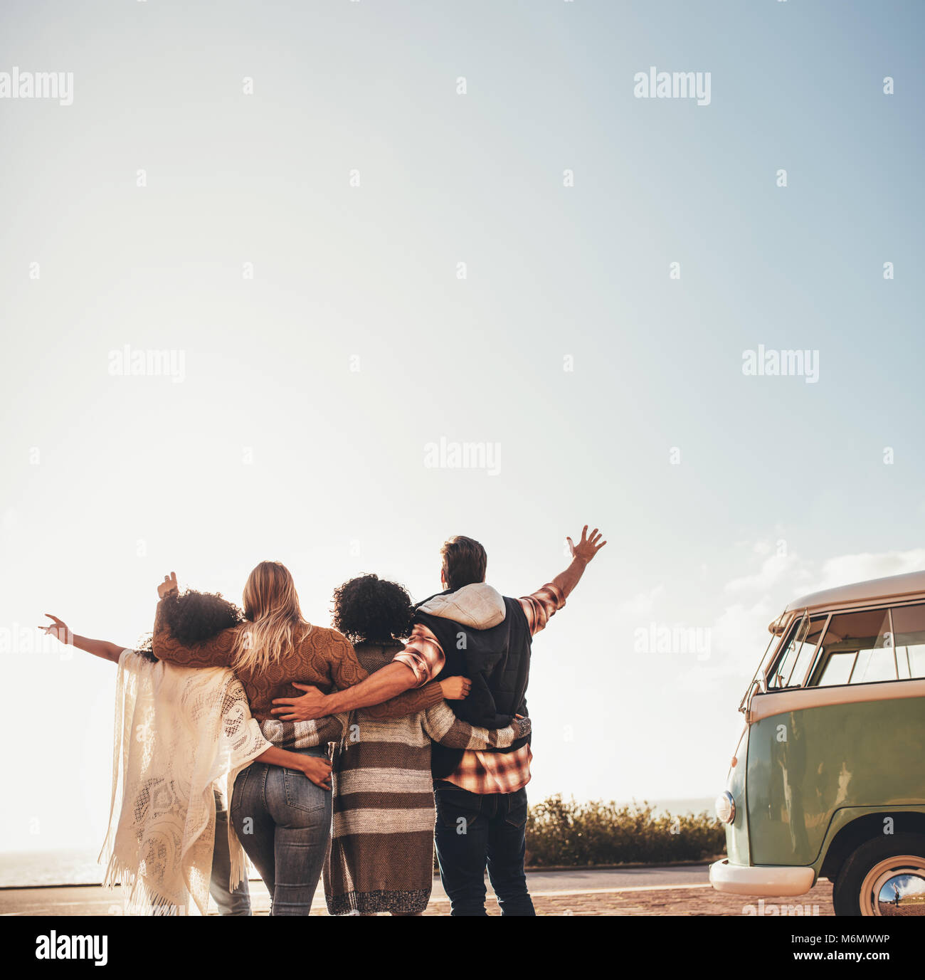 People enjoying during their road trip. Four friends standing together ...