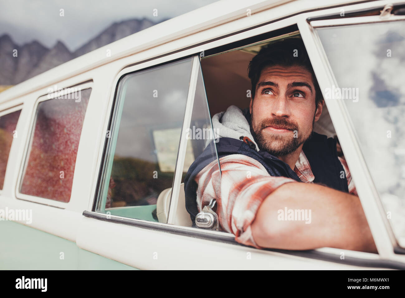 Handsome guy driving a van and looking outside the window. Man on a ...