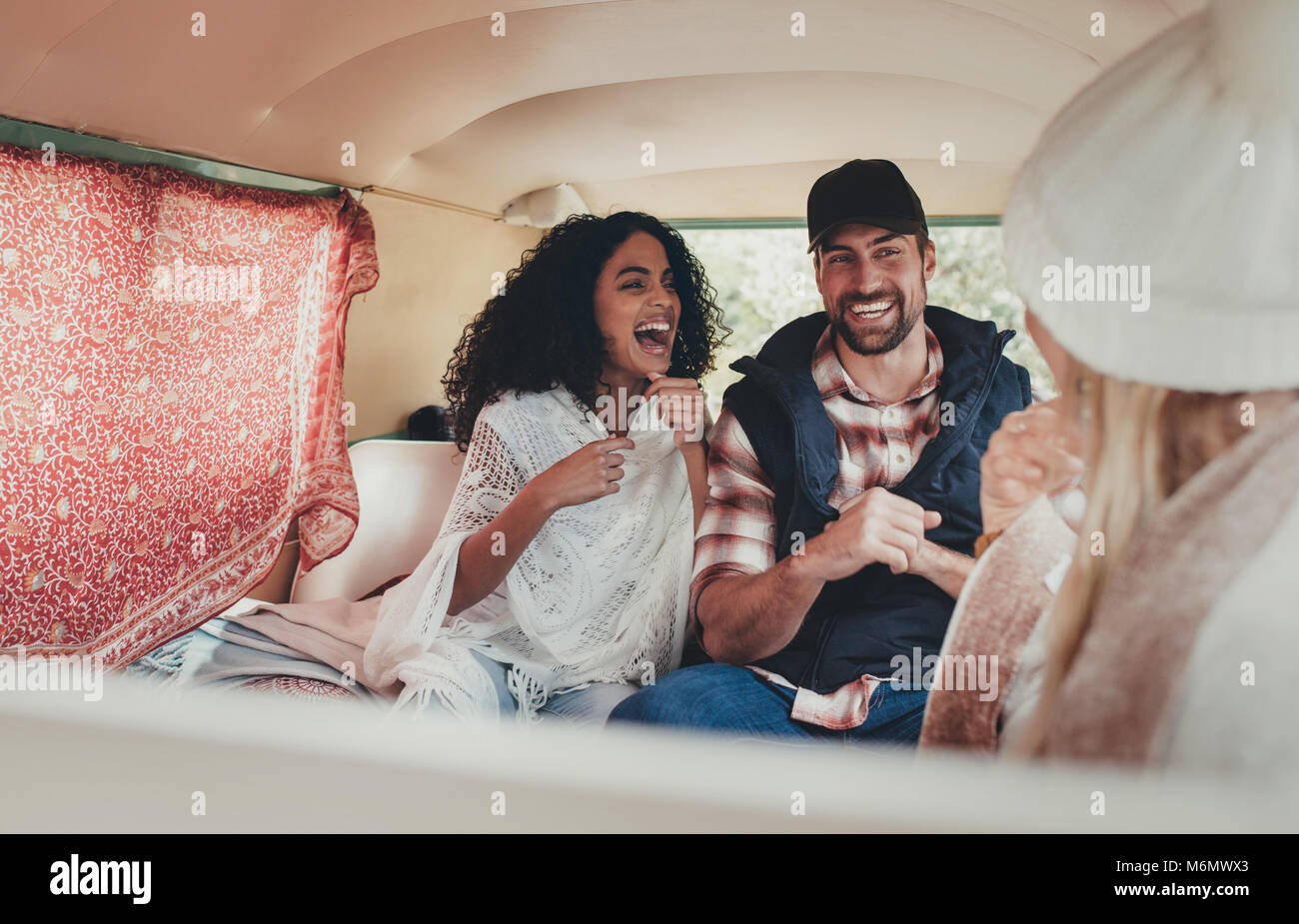 Friends on roadtrip smiling and laughing inside van. Man and woman ...