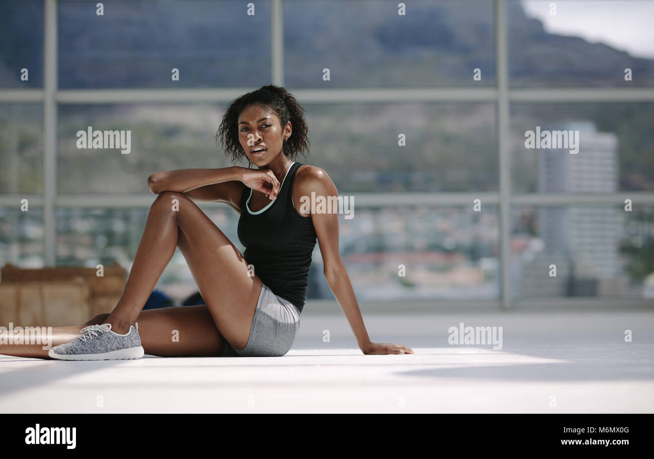 Healthy african woman relaxing after workout. Female at gym taking a ...