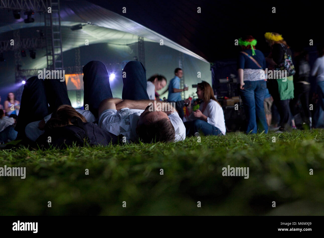 Members of the crowd at a a large outdoor concert take a rest and lay ...
