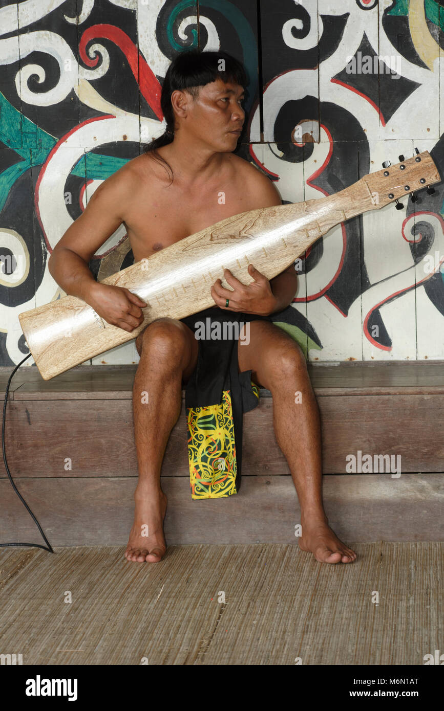 Native man playing traditional music on an electric Sape in the Orang ...