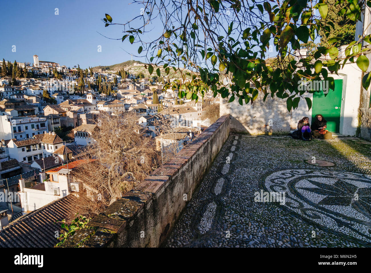 Two young women sit in La Churra square viewpoint looking at the Unesco ...