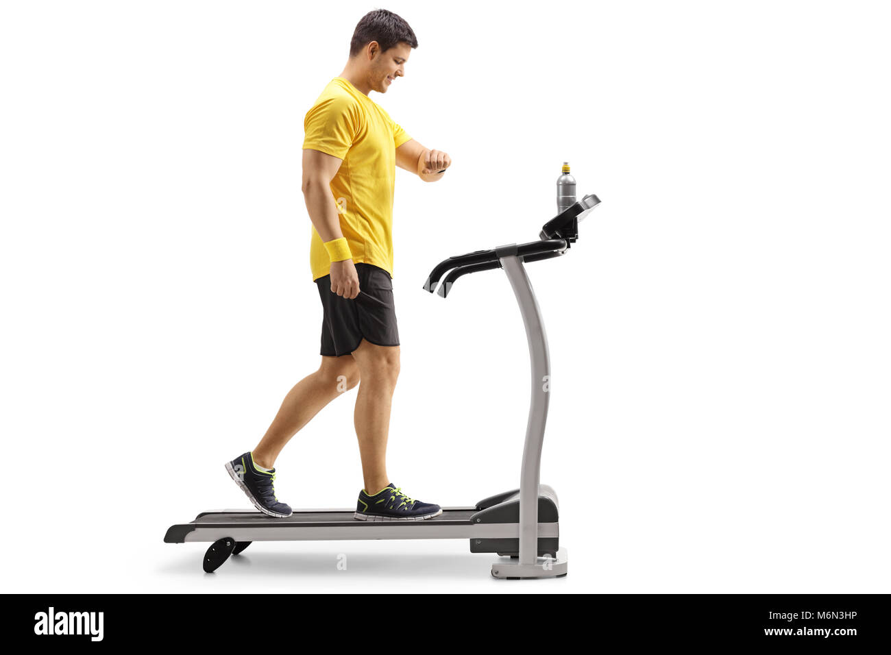 Full length profile shot of a young man walking on a treadmill and ...
