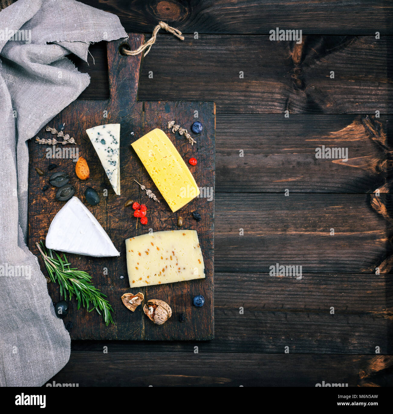 pieces of different cheeses on a brown wooden board: brie, roquefort ...